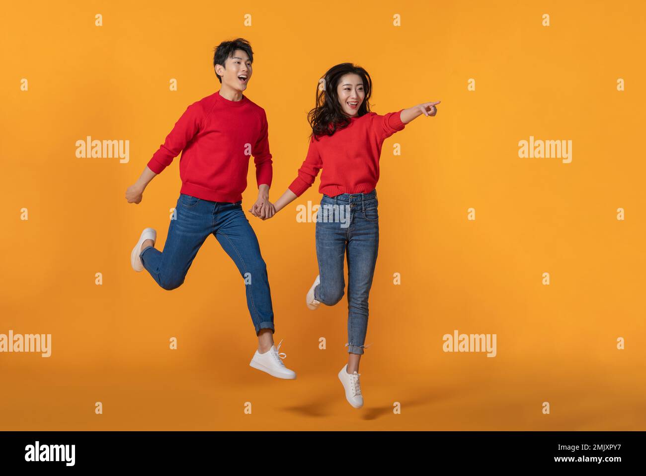 Happy young couple running hand in hand Stock Photo - Alamy