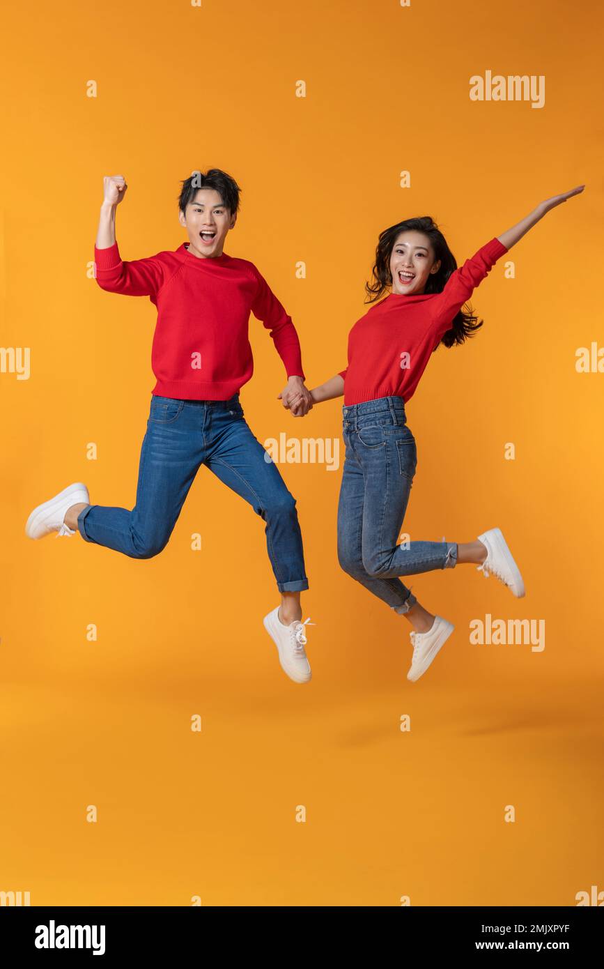 Happy young couple holding hands jumping Stock Photo - Alamy