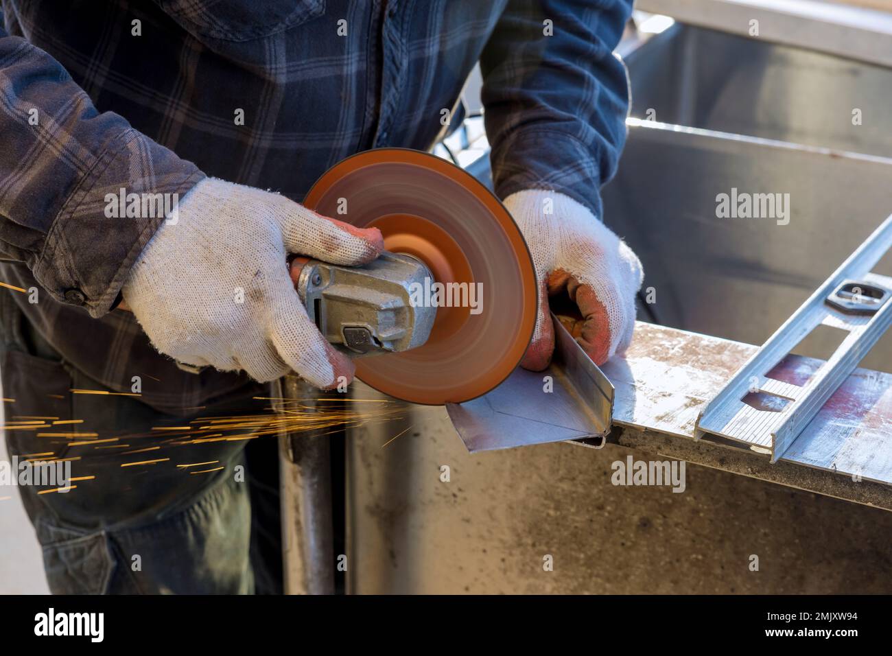 Worker cutting metal using grinder with sparks while grinding iron ...