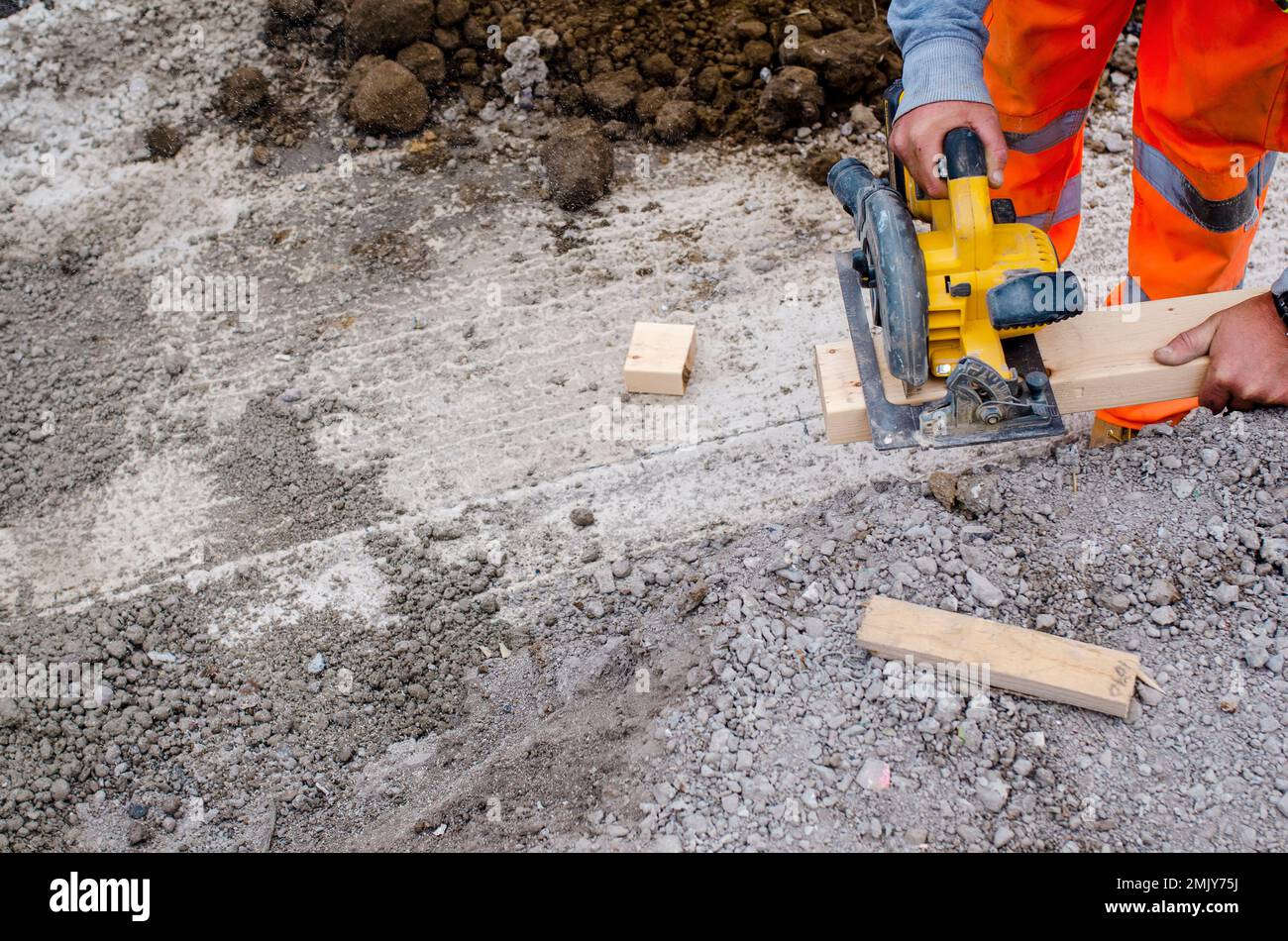 Builder cutting timber with a cordless battery-powered circular saw on ...