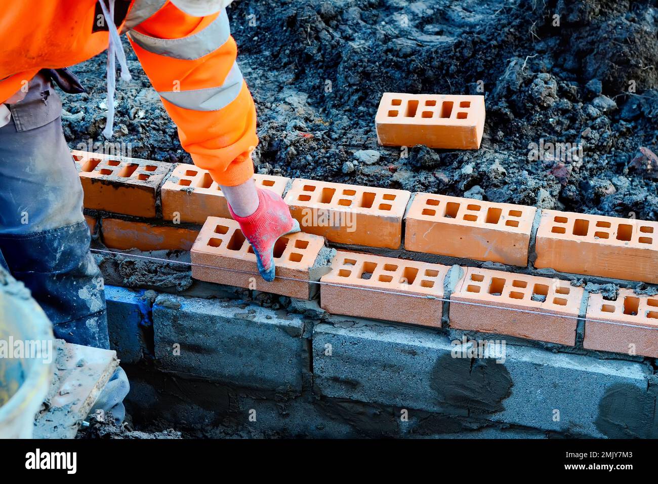 Industrial bricklayer laying bricks on cement mix on construction site ...