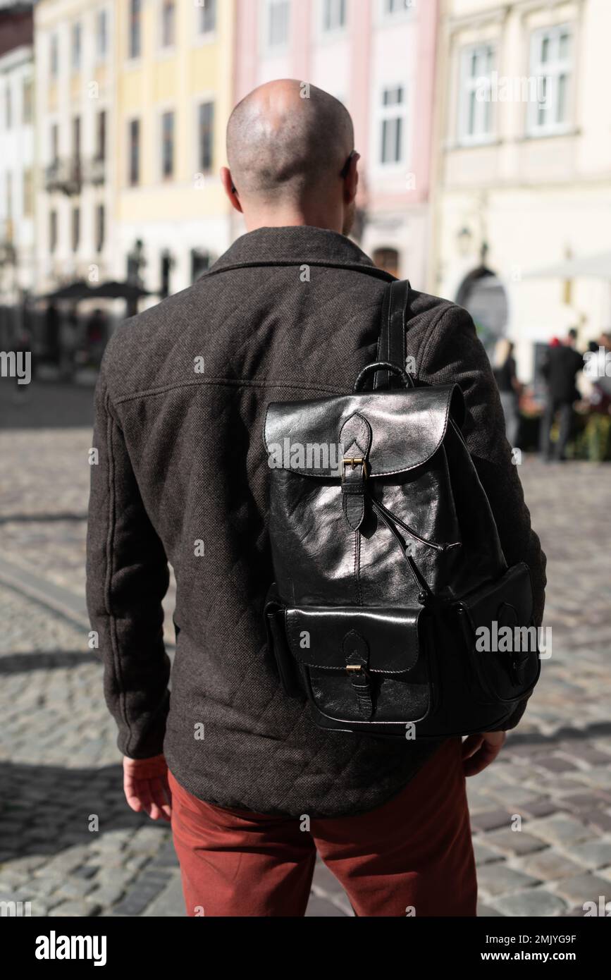 Part photo of a man with a black leather backpack with antique and ...