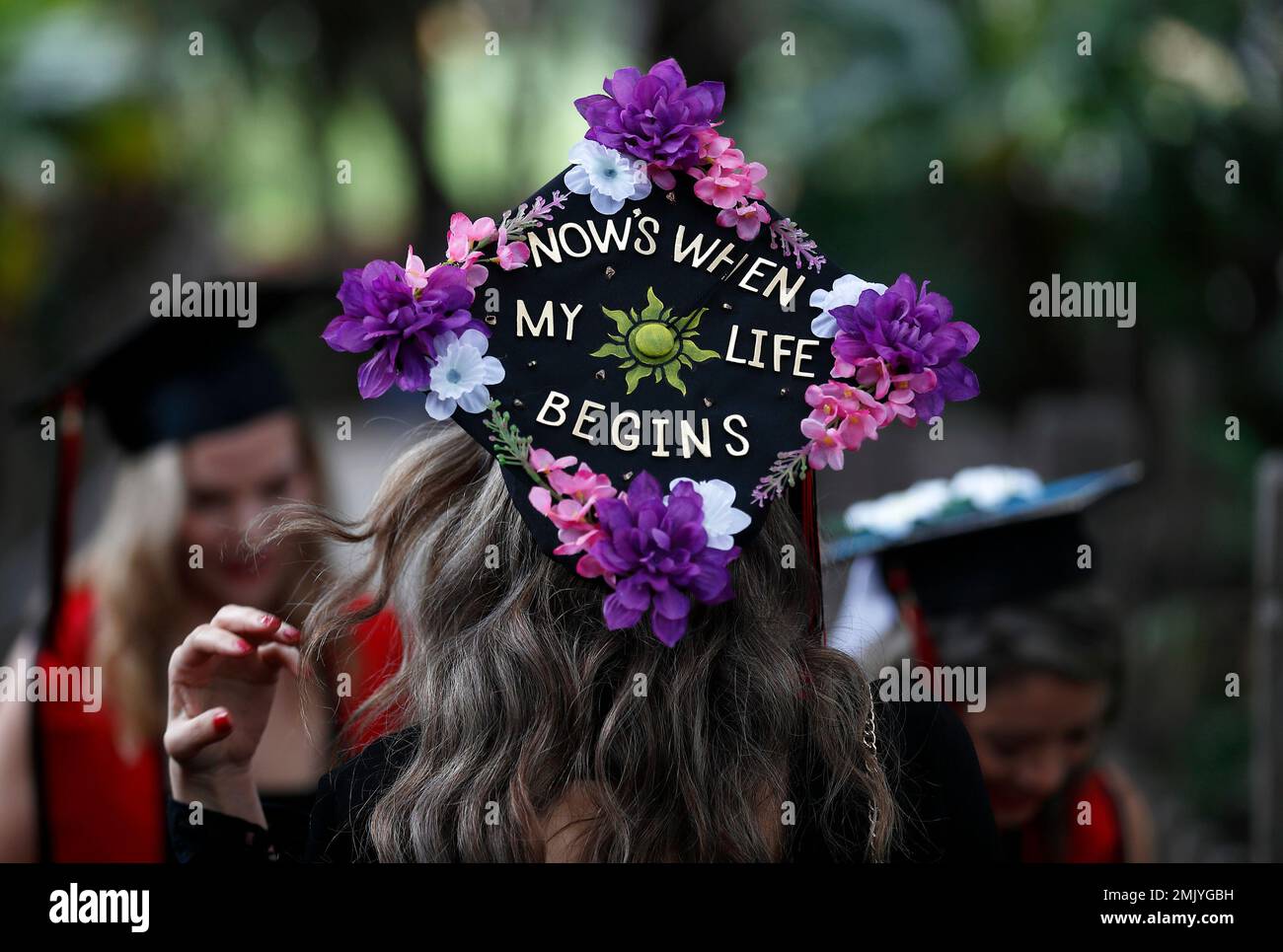 Alison Vargas, center, wears a graduation cap adorned with words and ...