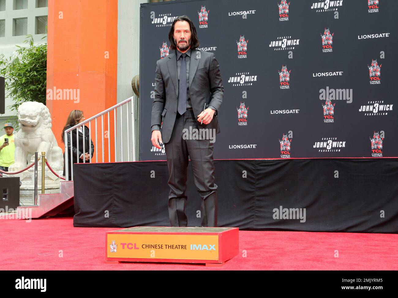 Keanu Reeves signs a cement slab during a hand and footprint ceremony ...