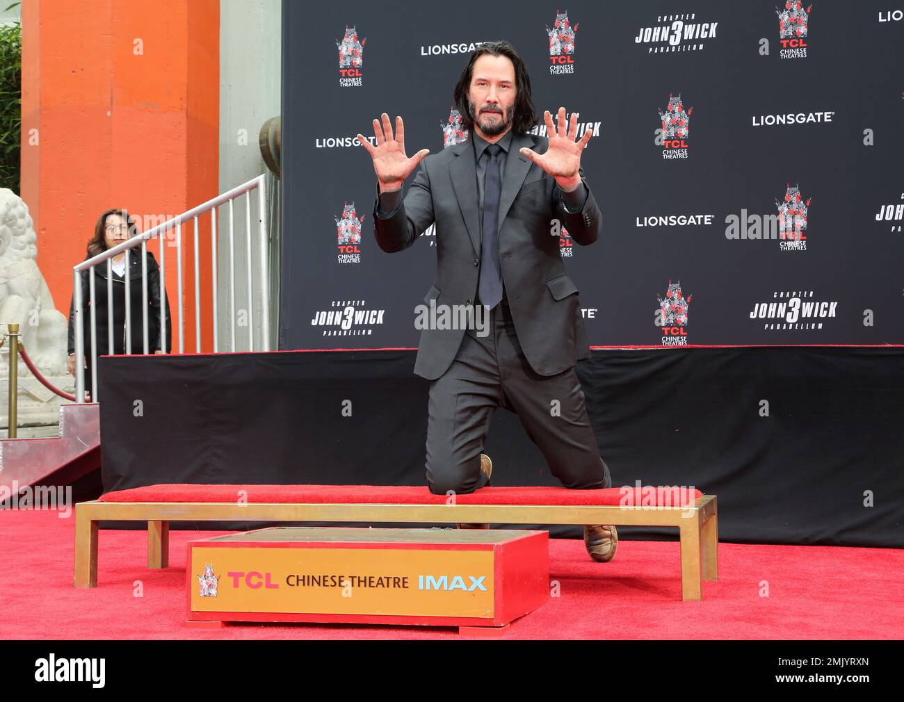 Keanu Reeves signs a cement slab during a hand and footprint ceremony ...