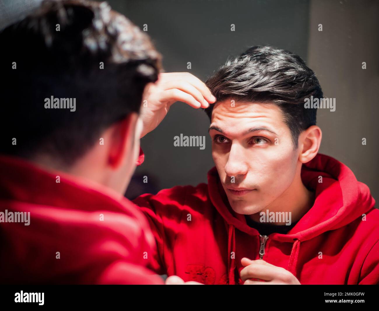 Handsome man looking at his face in a mirror Stock Photo - Alamy