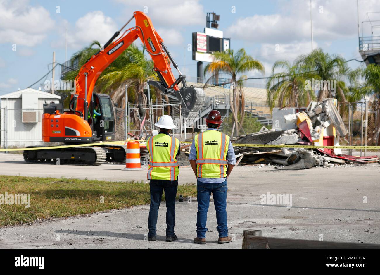 Workers watch as an excavator knocks down an old ticket booth during a ...