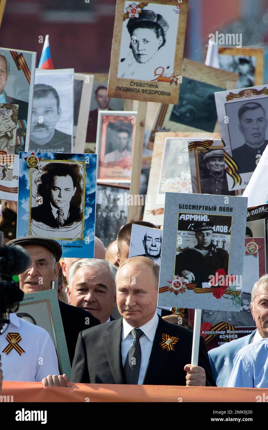 Russian President Vladimir Putin, center, holds a portrait of his ...