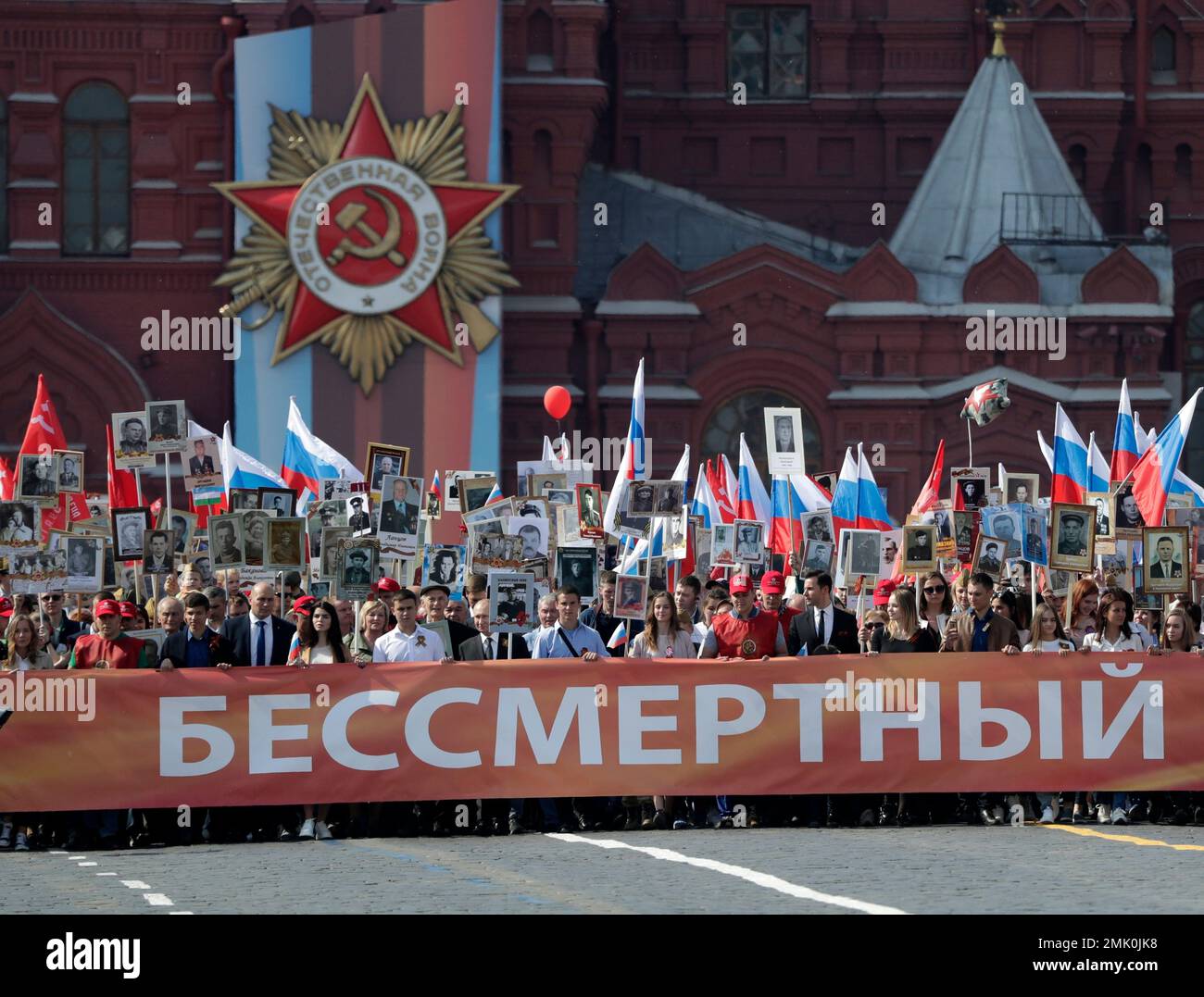 Russian President Vladimir Putin, center left, holds a portrait of his ...