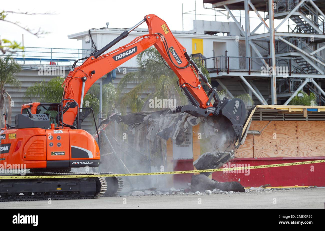 An excavator knocks down an old ticket booth during a demolition ...