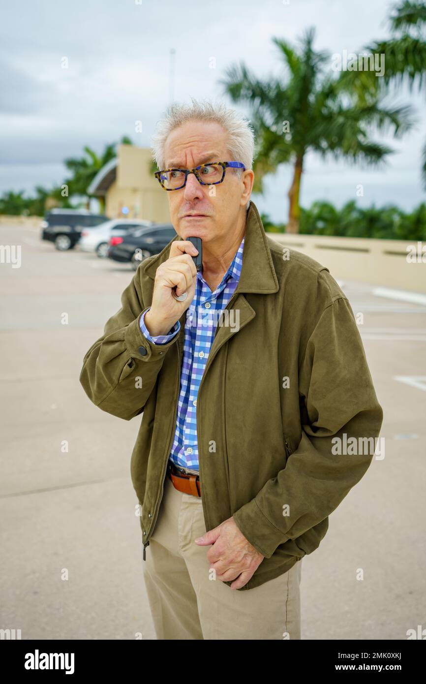 Old man looking for his car in a parking lot by pushing the unlock ...