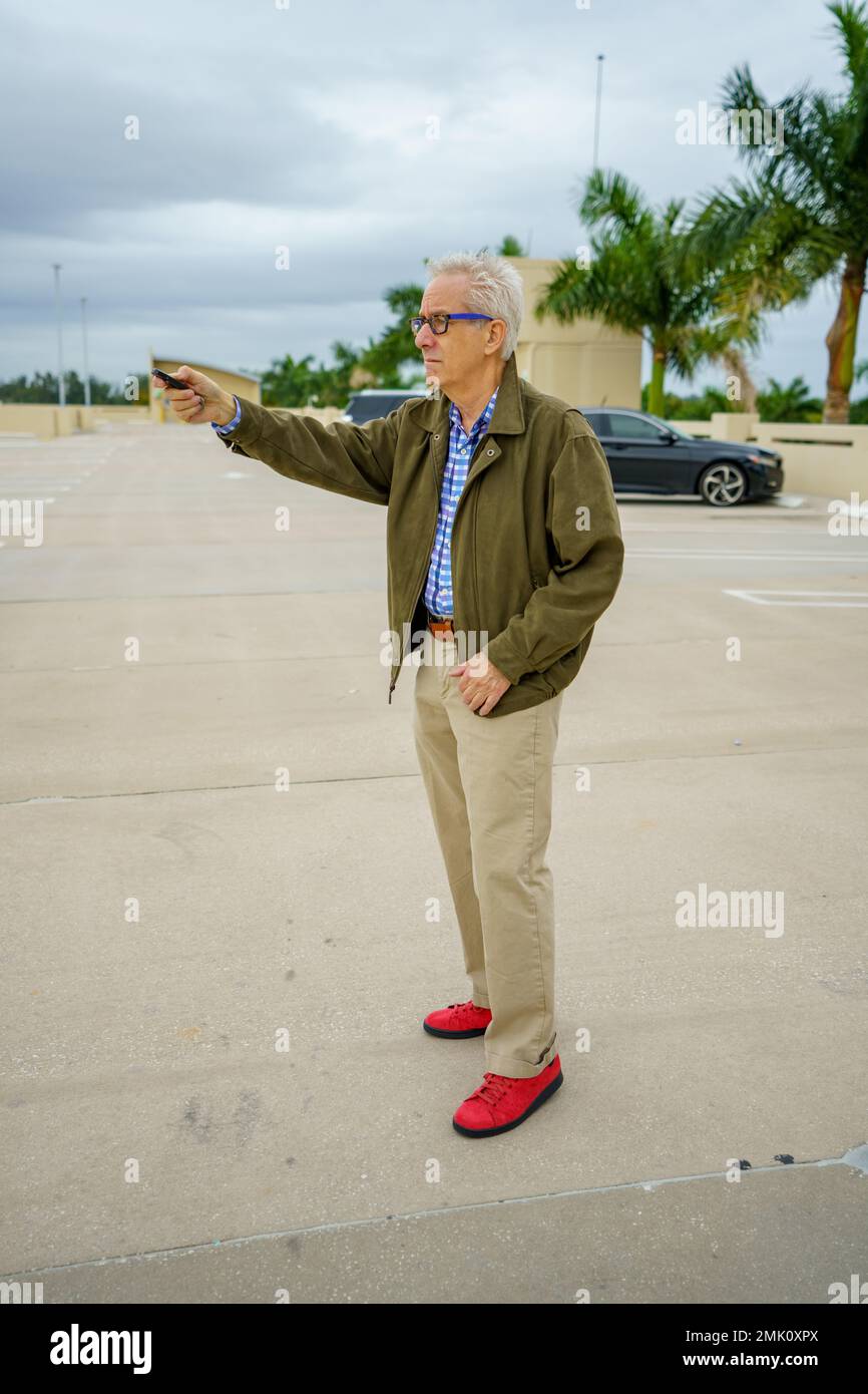 Old man looking for his car in a parking lot by pushing the unlock ...