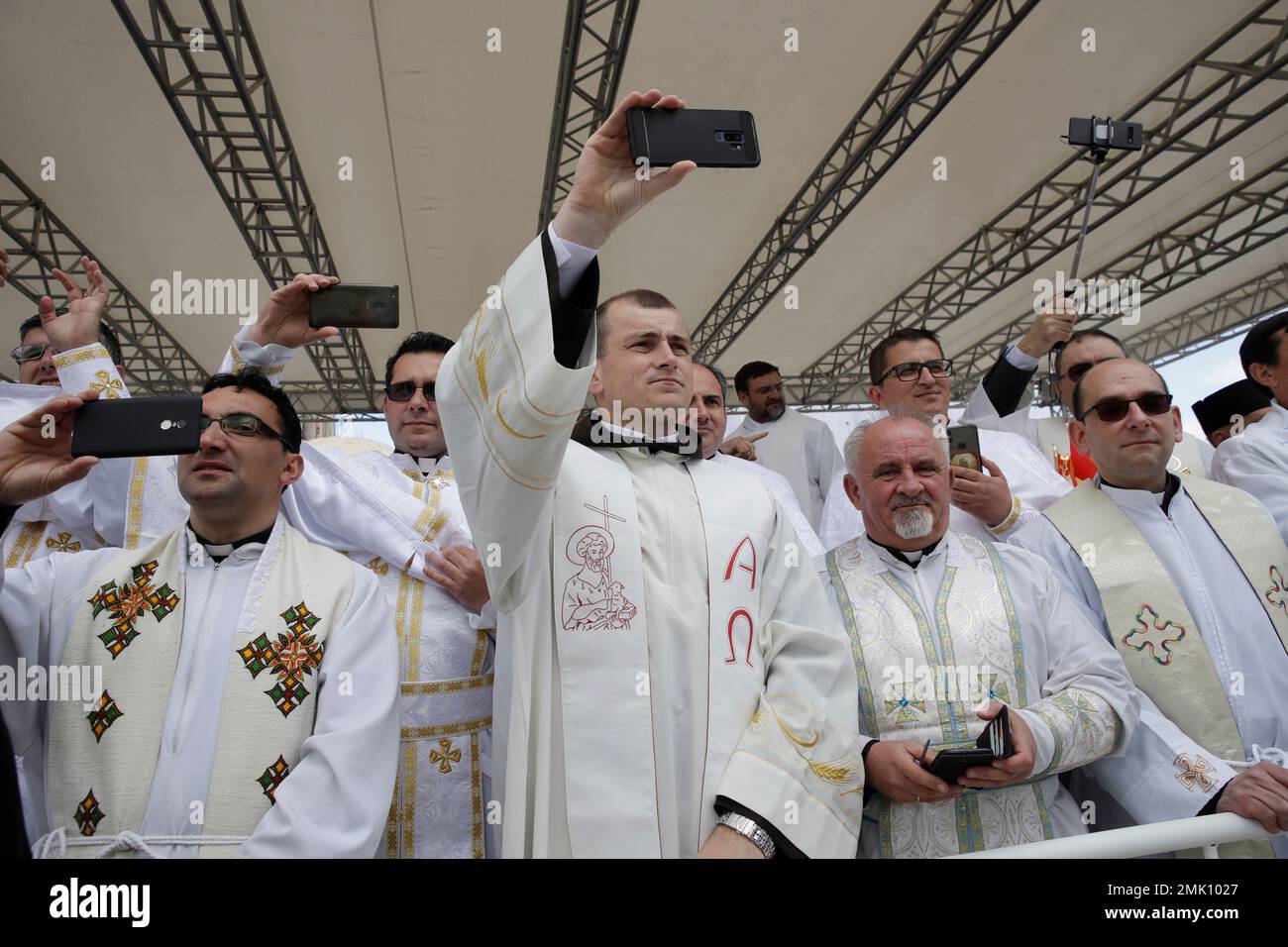 Priests take pictures of Pope Francis as he arrives to celebrate Mass ...