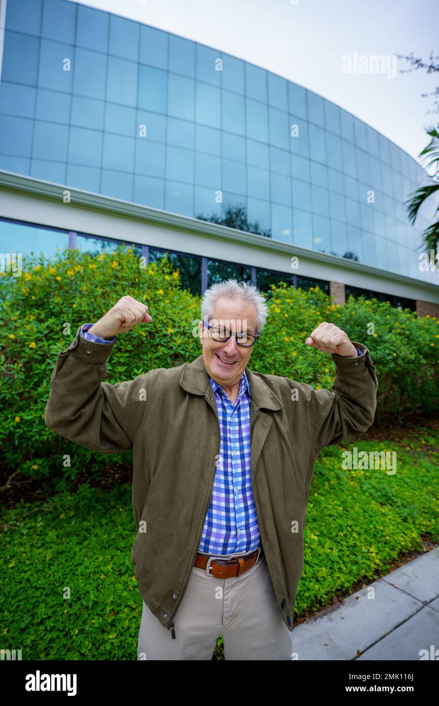 Senior man flexing his muscles by an office building Stock Photo - Alamy