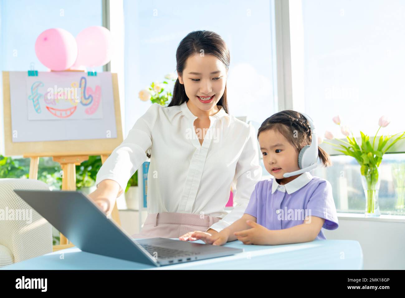 The teacher use the computer with little girl Stock Photo - Alamy