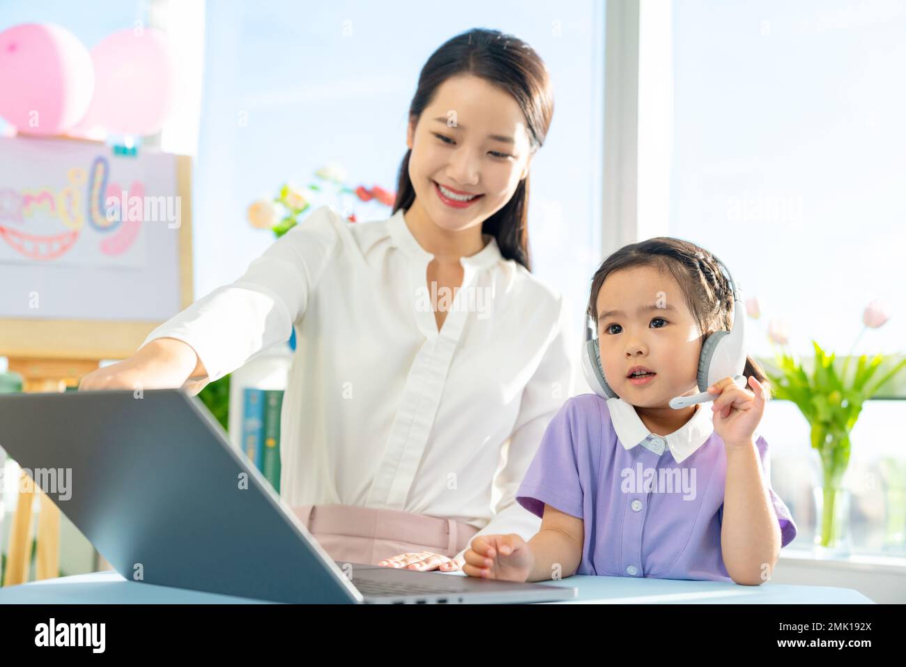 The teacher use the computer with little girl Stock Photo - Alamy