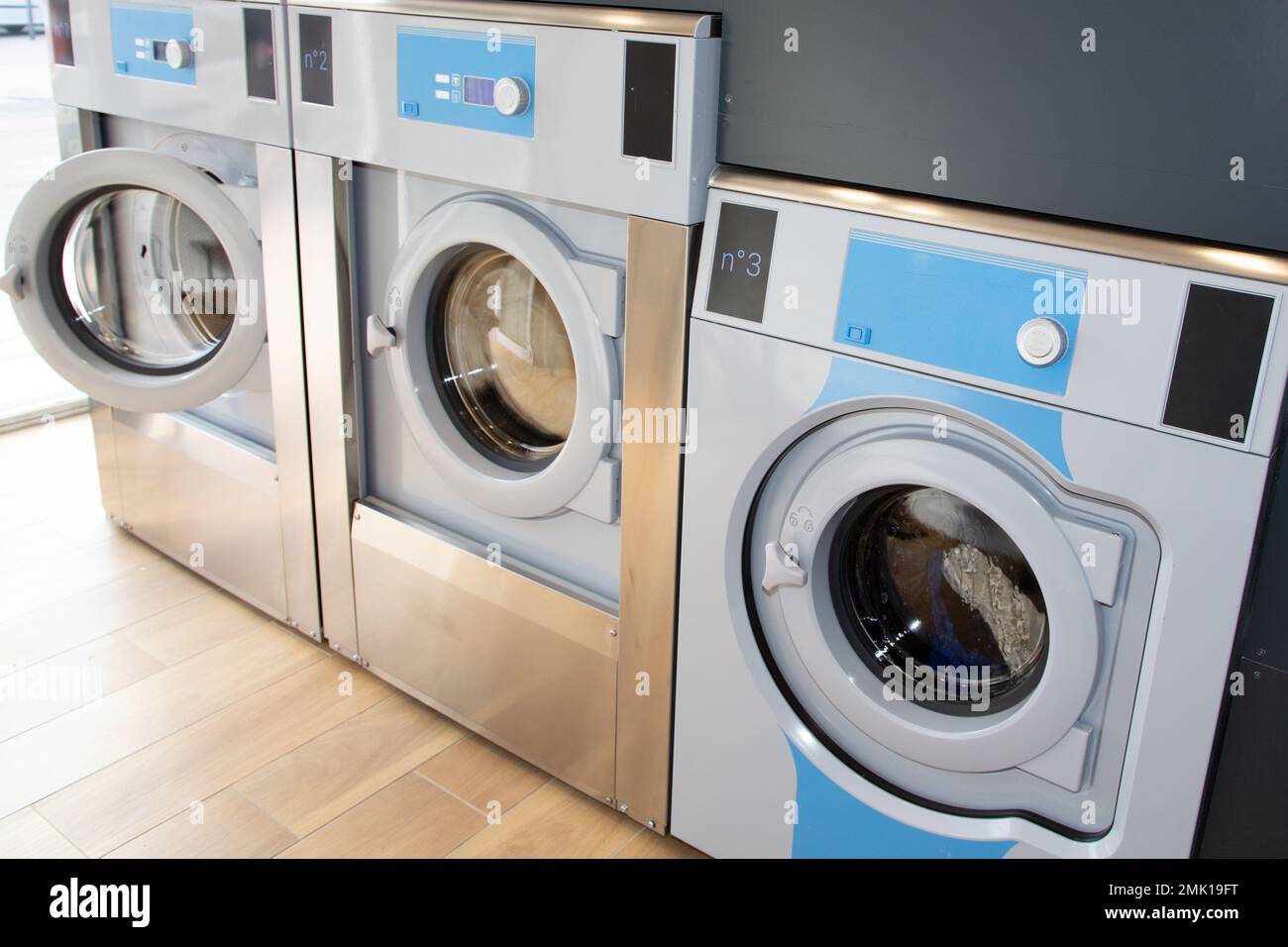 row of industrial washing machines in a public Laundromat Dryers ...