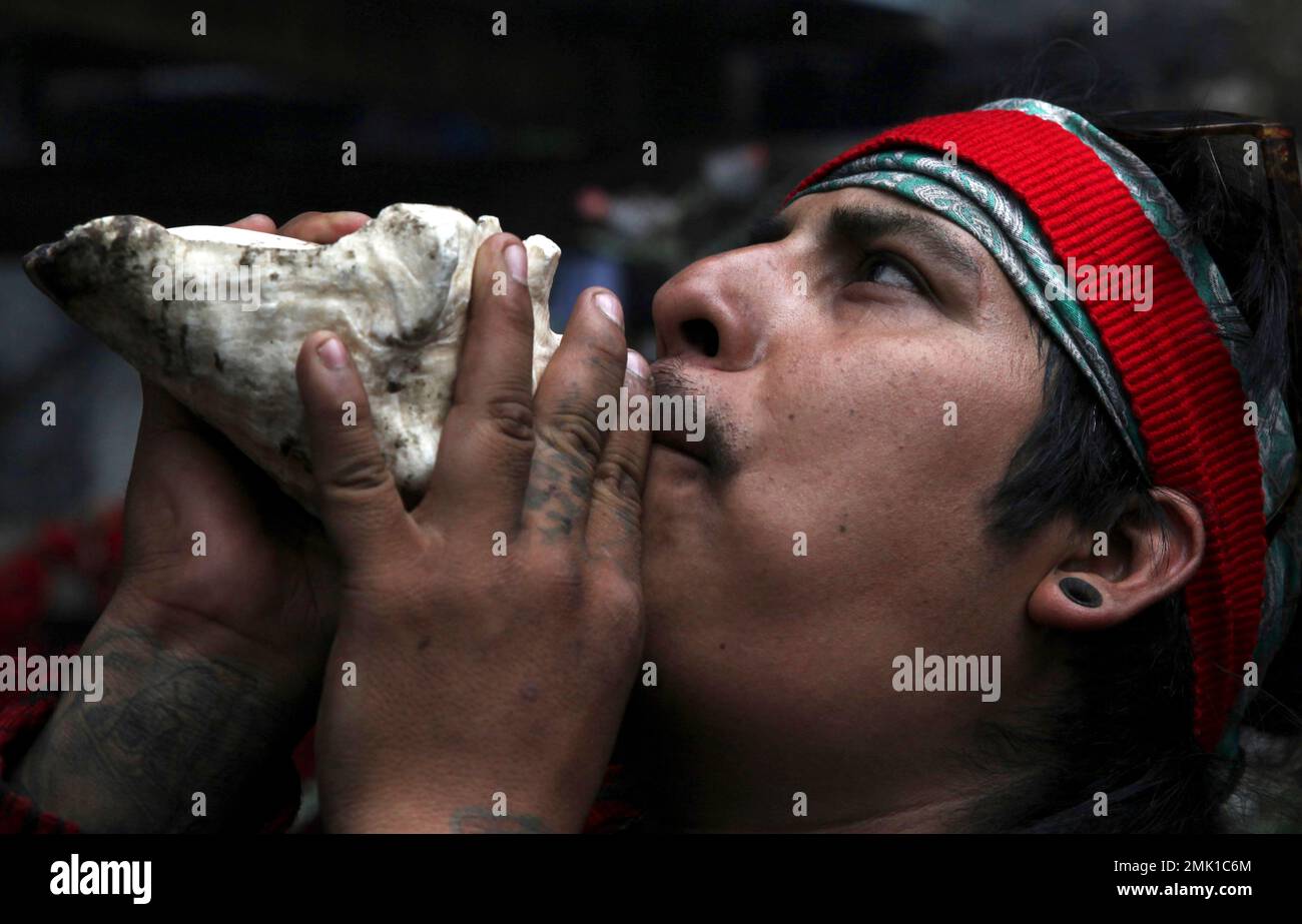 In this Friday, May 3, 2019 photo, a resident blows on a conch shell to ...