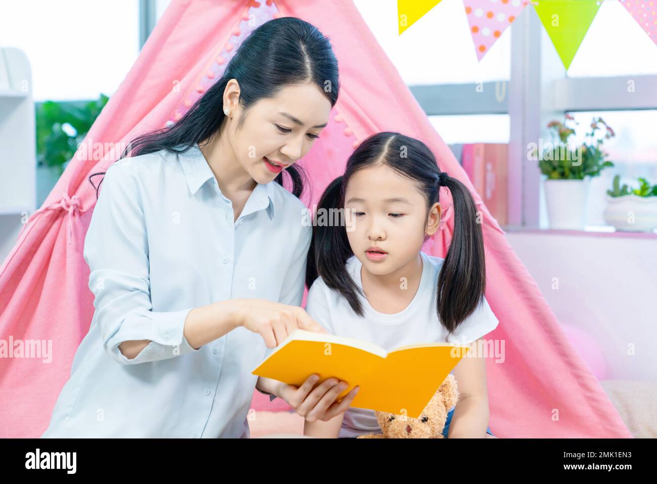 The little girl and her mother read a book together Stock Photo - Alamy