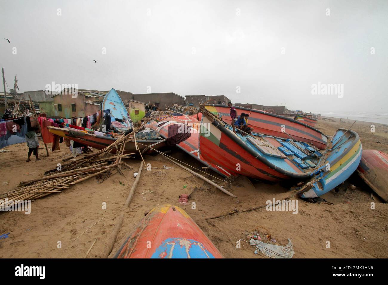 Children sit on a boat damaged by Cyclone Fani in the Penthakata ...