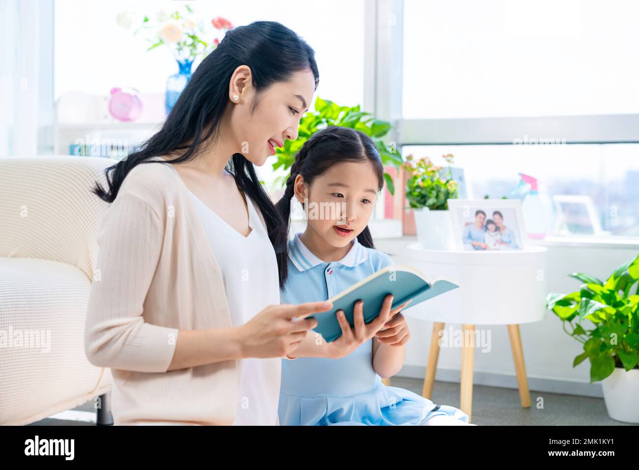 The little girl and her mother read a book together Stock Photo - Alamy
