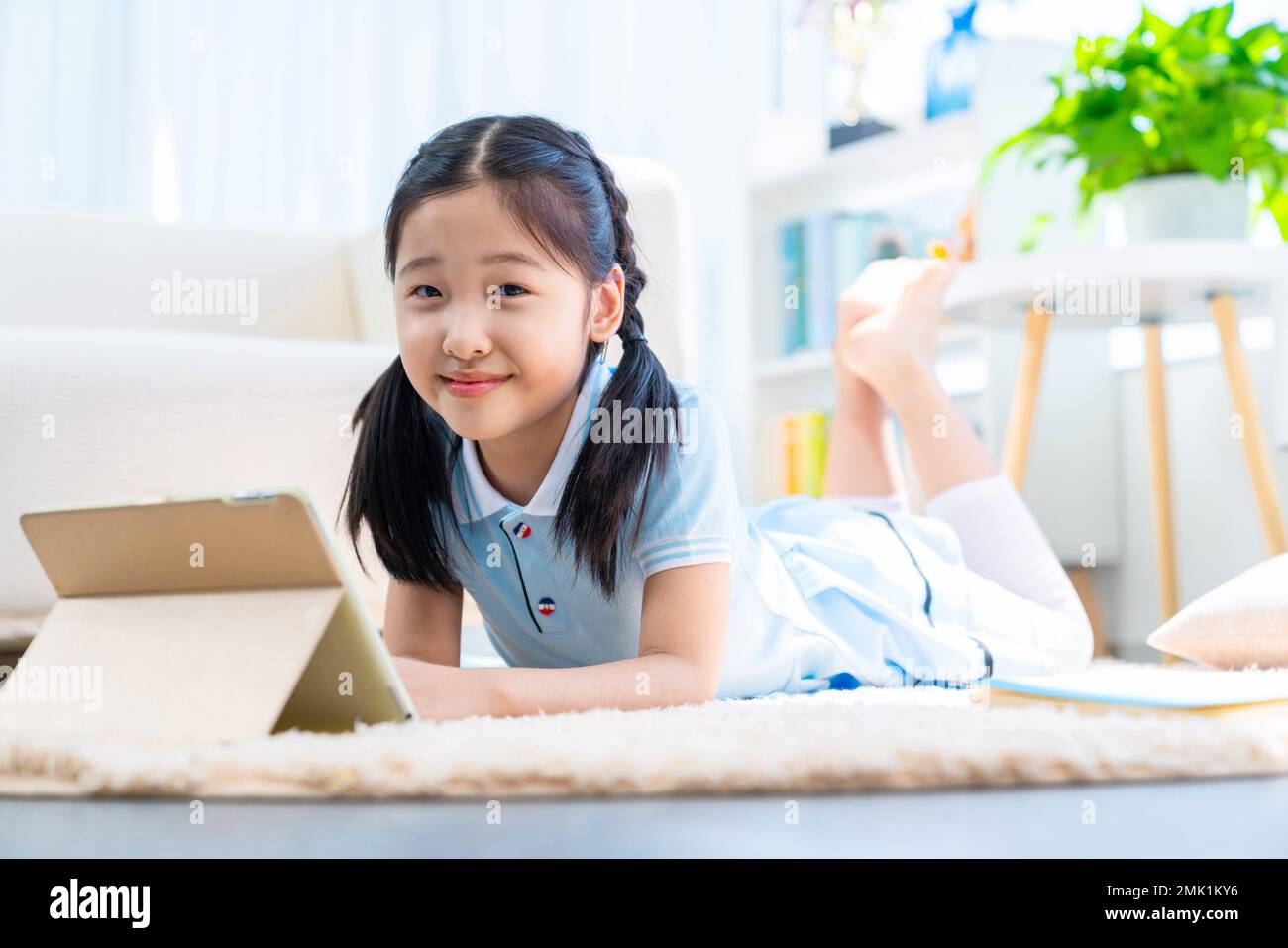 The little girl use tablet computers on the carpet Stock Photo - Alamy