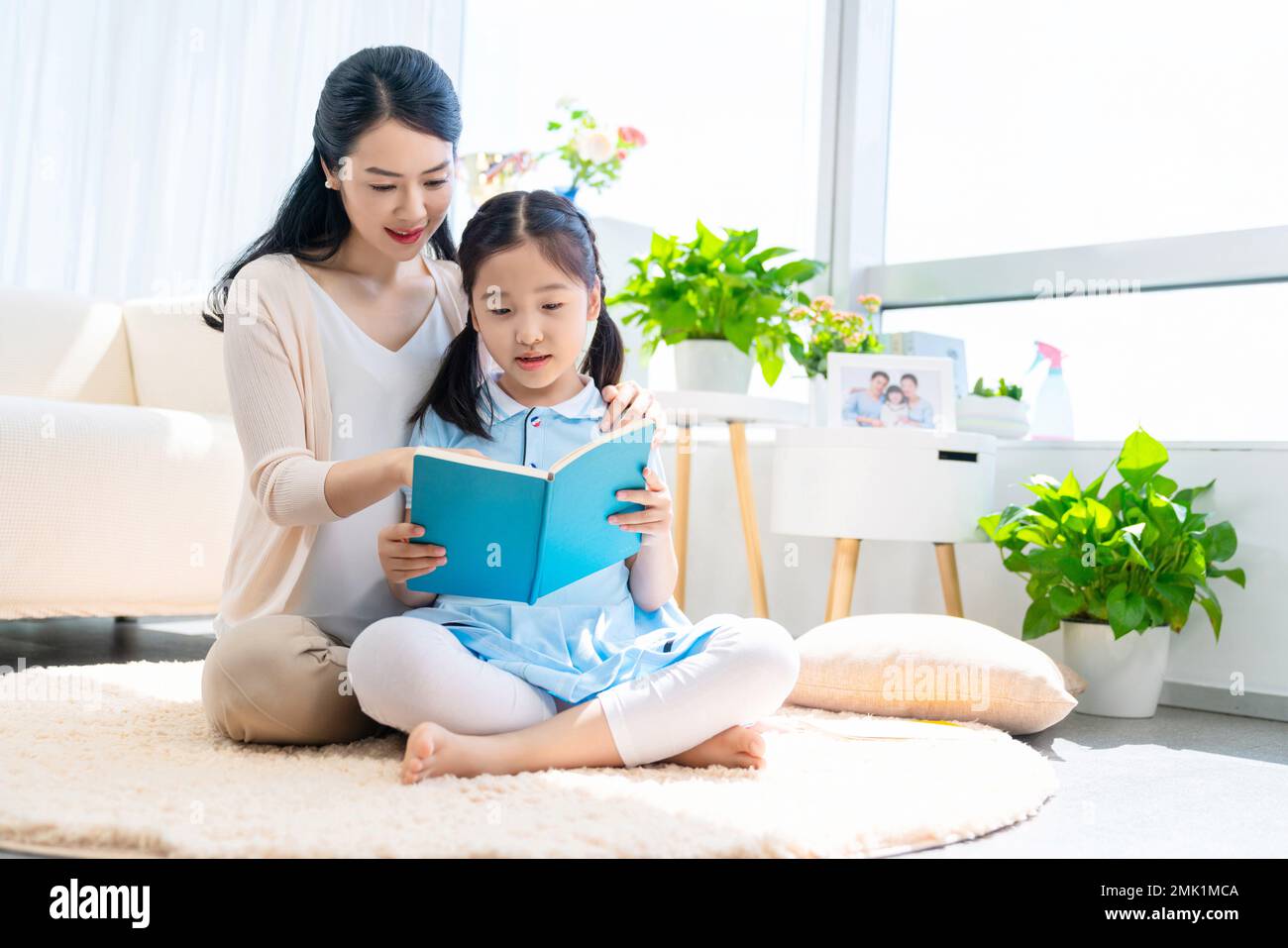 The little girl and her mother read a book together Stock Photo - Alamy