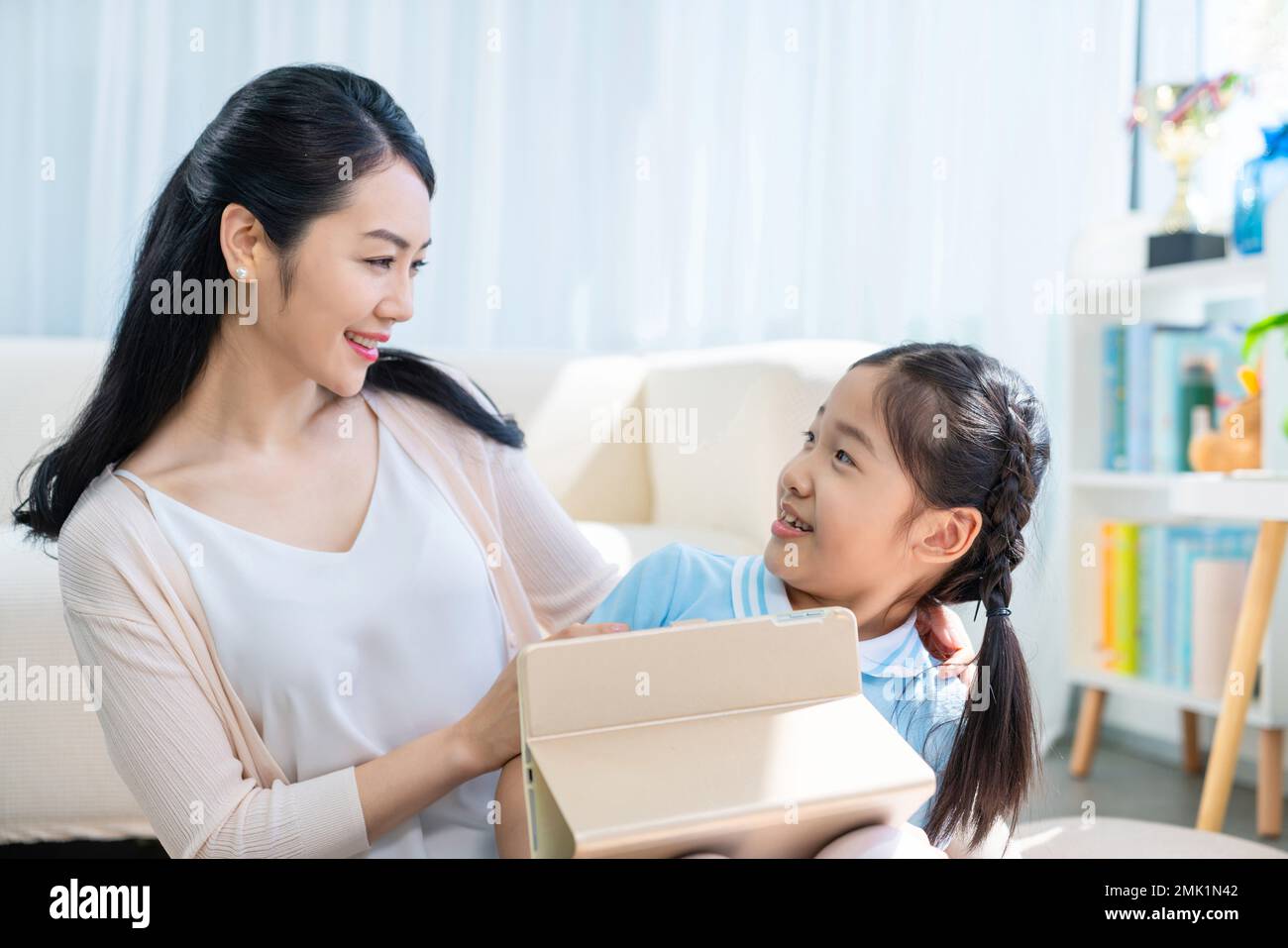 The little girl with her mother to use tablet Stock Photo - Alamy