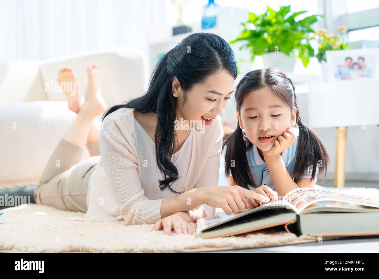 The little girl and her mother read a book together Stock Photo - Alamy