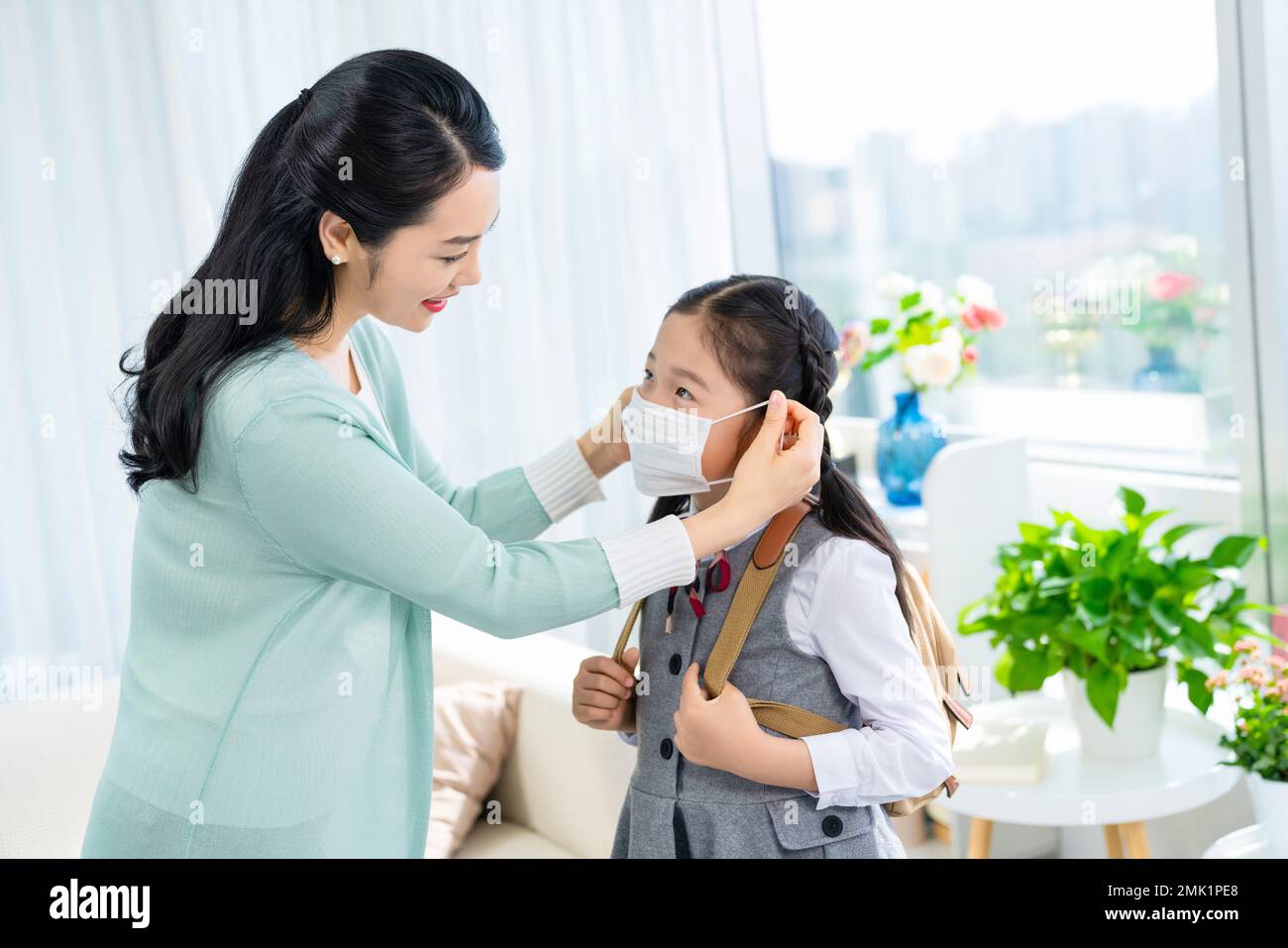 Mother to daughter wearing a mask Stock Photo - Alamy