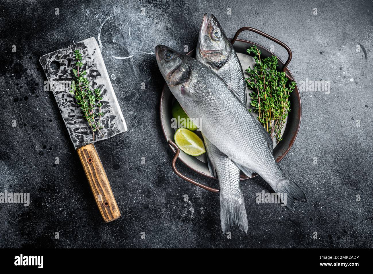 Fresh Raw Sea Bass, Labrax fish with herbs and lime. Black background ...