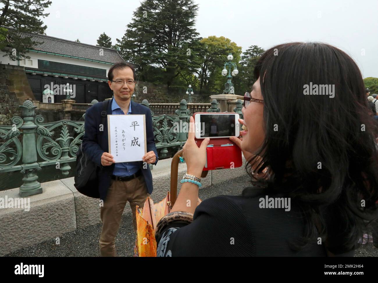 Hitoshi Sato, a university official, with a sign reading "Heisei, Thank ...