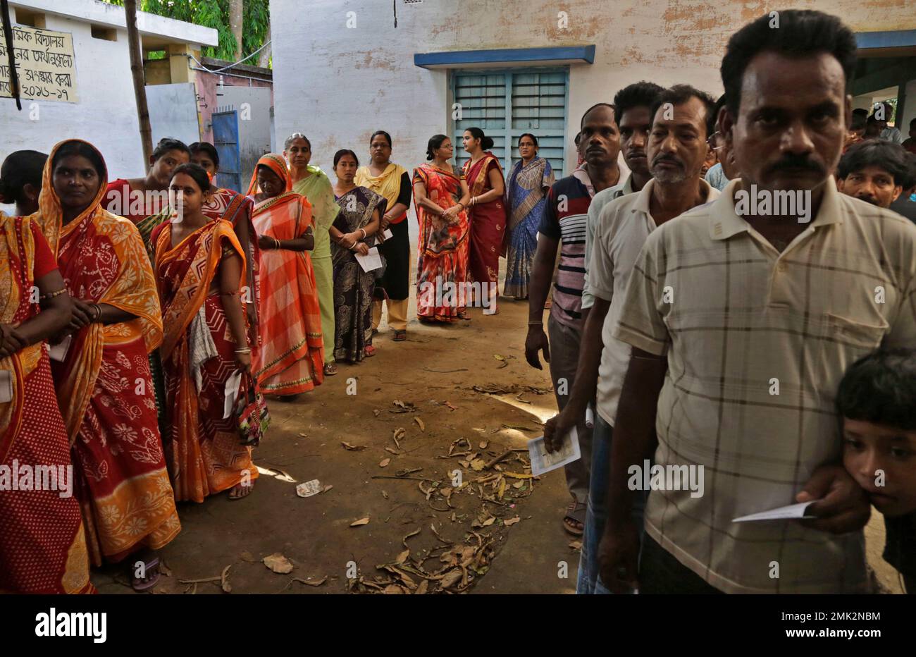 Indian men and women stand in queue to cast their votes at a polling ...