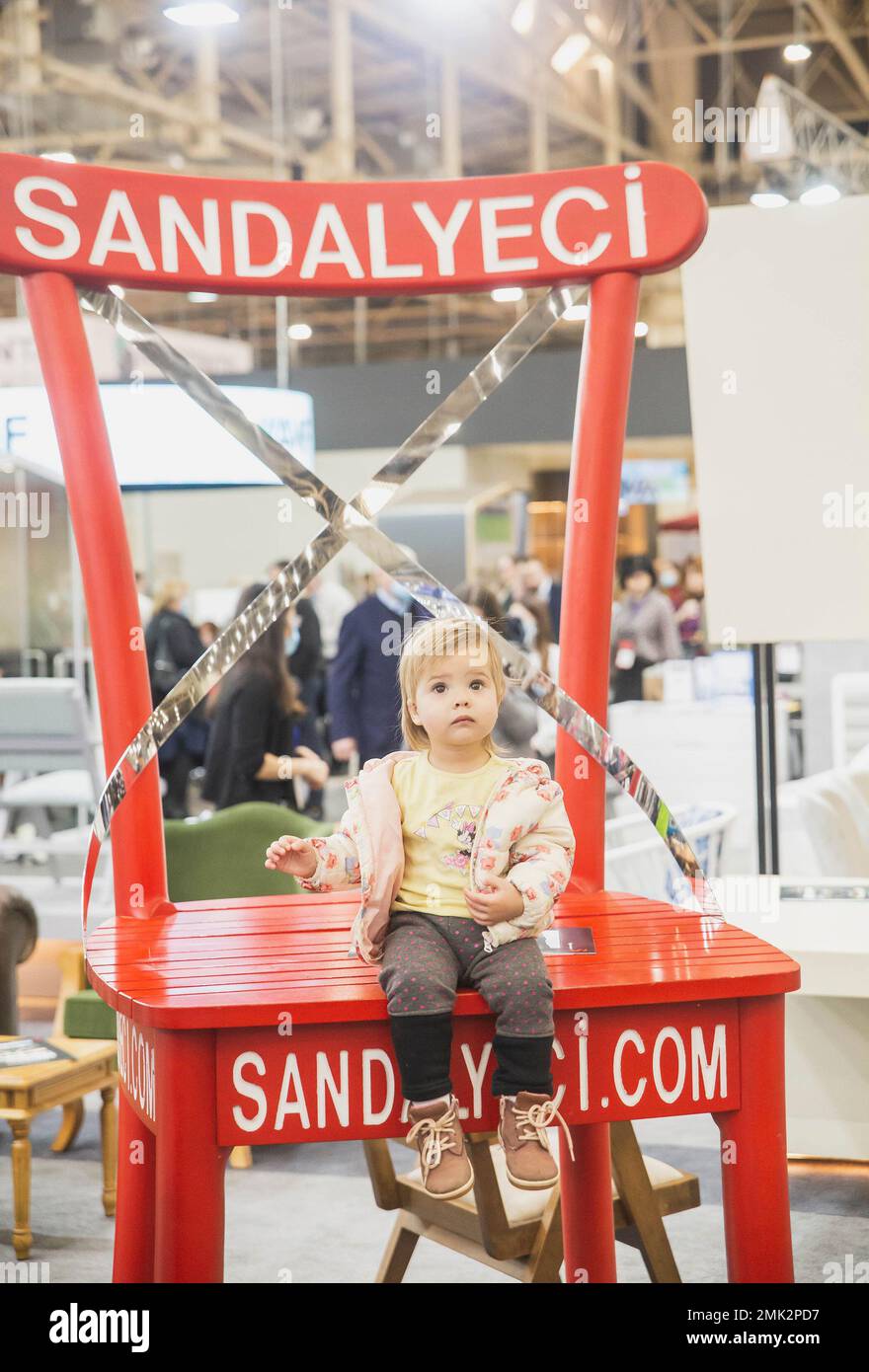 baby sitting on a huge chair at the international furniture exhibition ...