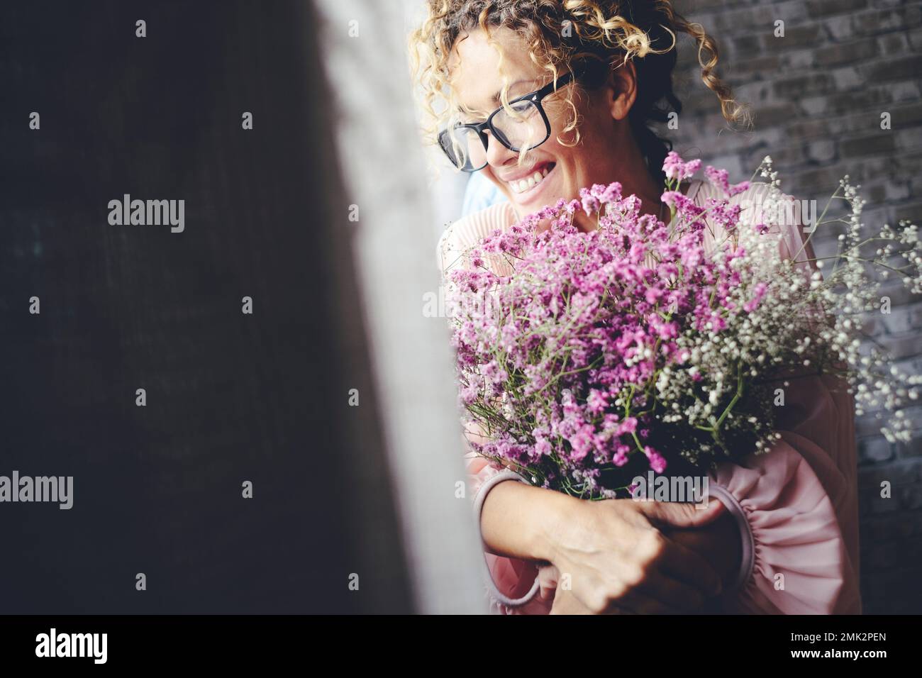 Overjoyed happy woman smiling and hugging a floreal flowers bouquet at ...