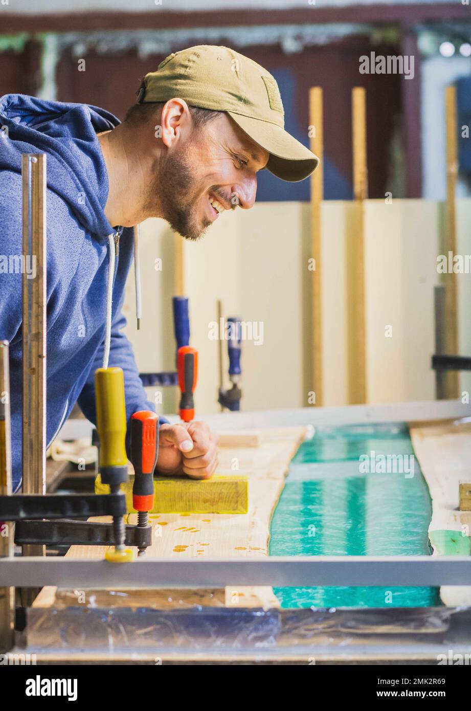 carpenter admires an oak table with turquoise epoxy resin Stock Photo ...