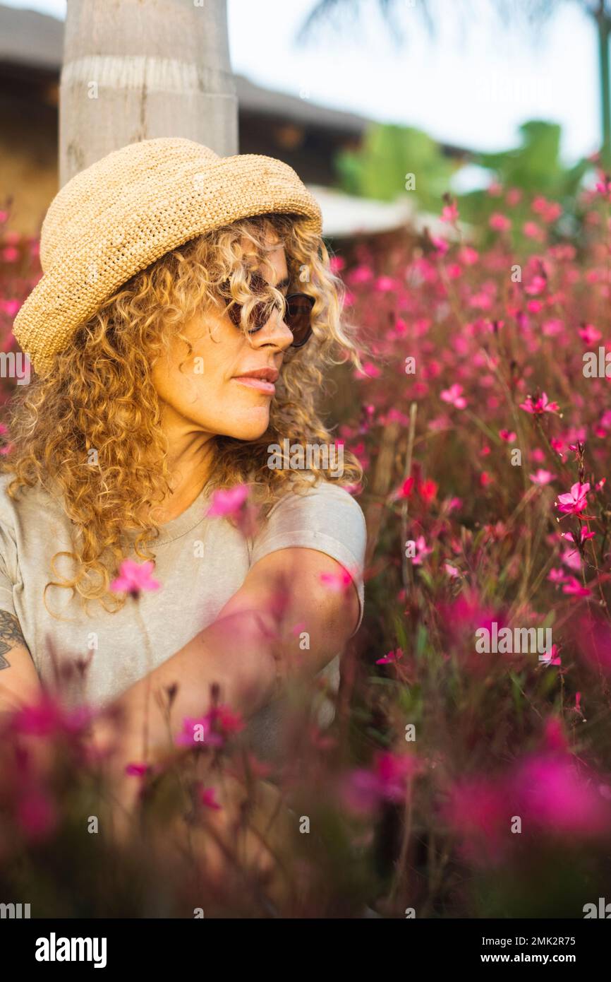 One pretty woman sitting in the flowers meadow having relax in outdoor ...