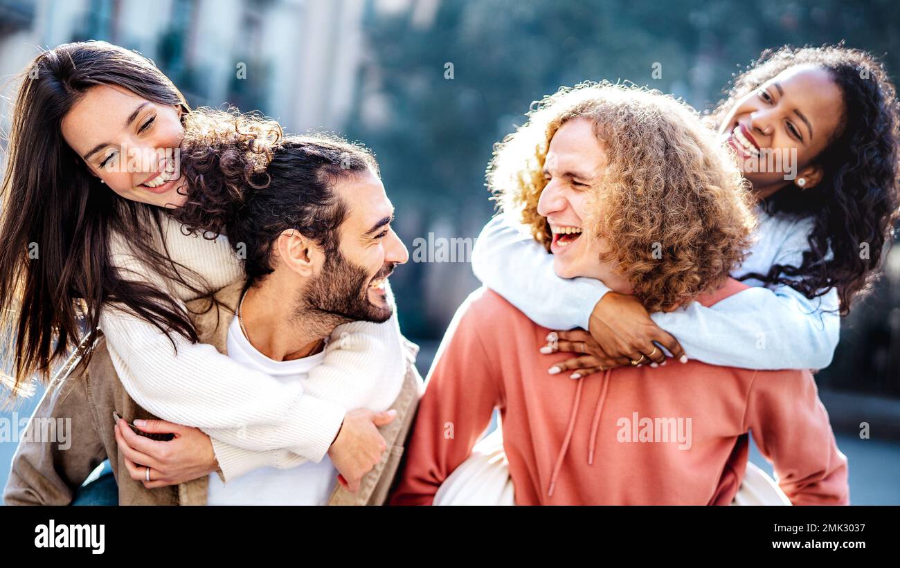 Young multicultural couples walking at travel location on piggyback ...