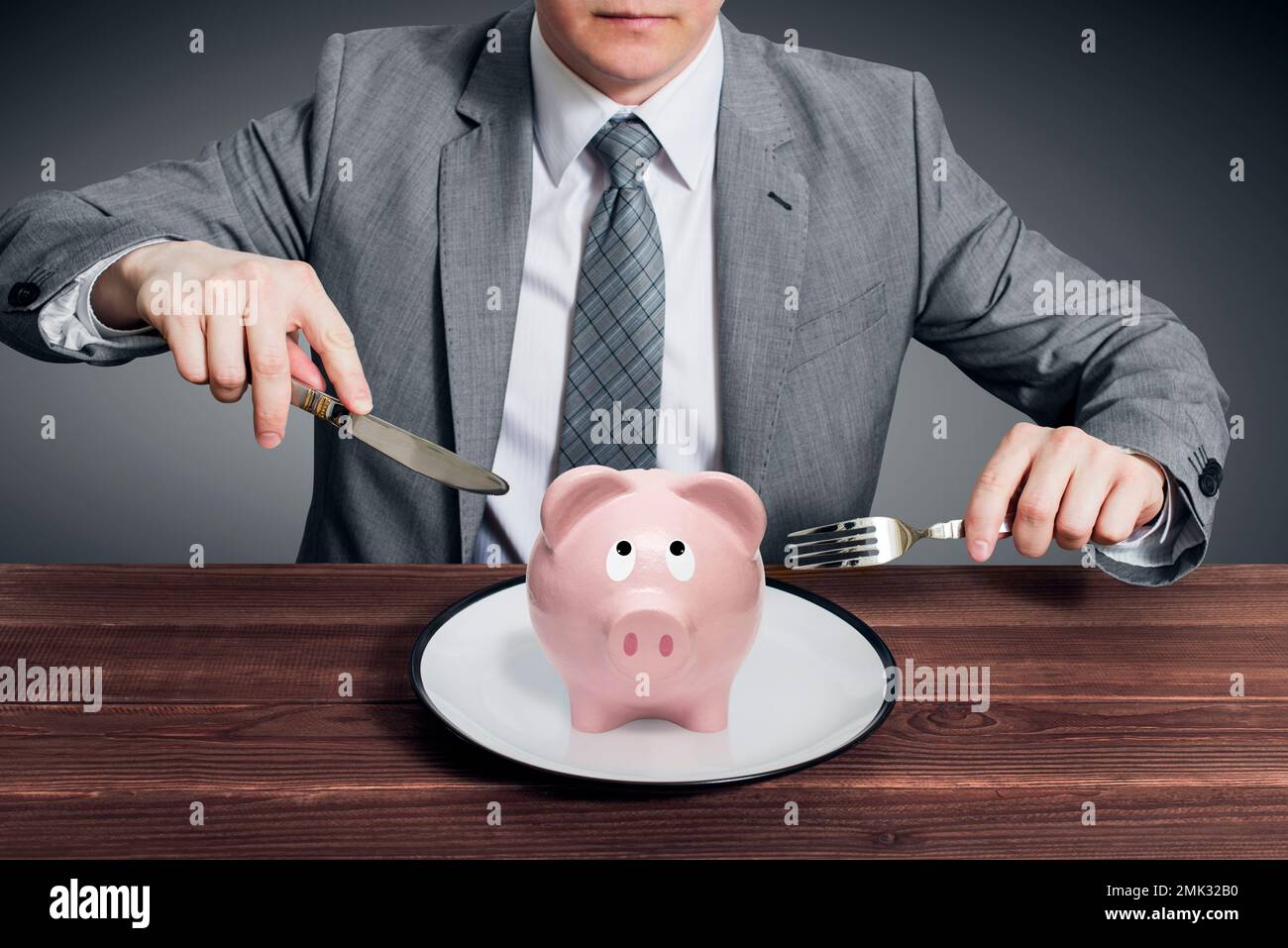 Businessman eating piggy bank. Business concept Stock Photo - Alamy
