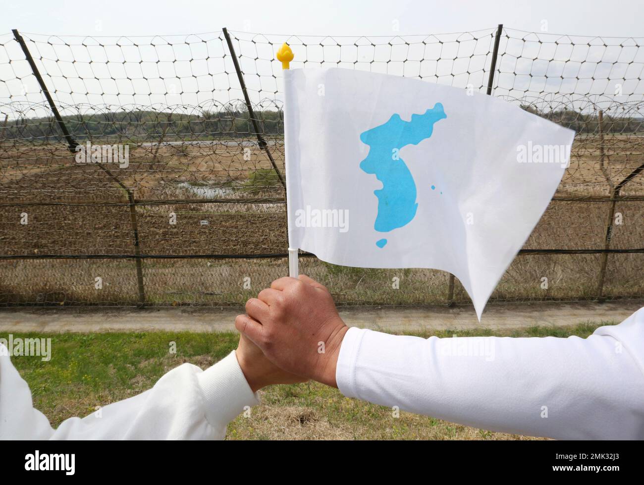 Participants hold a unification flag in front of the military wire ...