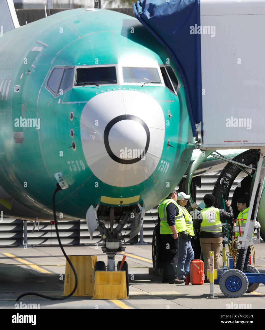 Workers stand near an engine on a Boeing 737 MAX 8 airplane being built ...