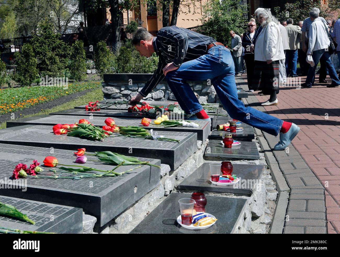 Ukrainians lay flowers by the tombstone that bears their relative's ...