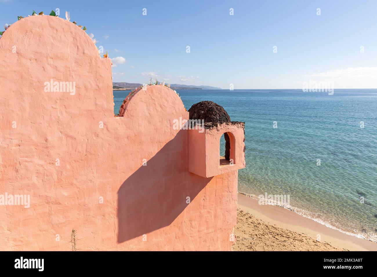 A salmon-coloured wall, bristling with shards of glass, marking the ...