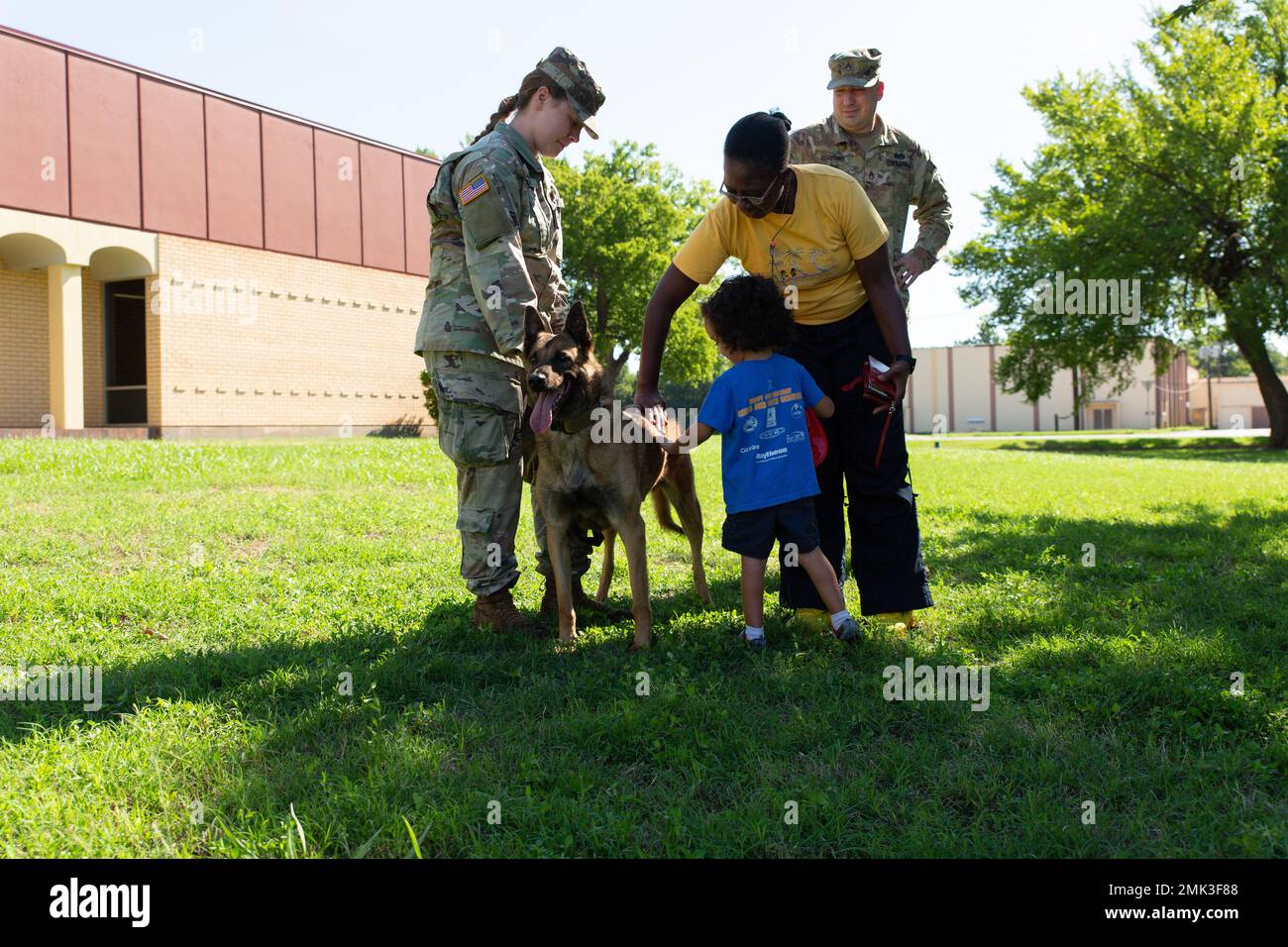 A young boy and his mother pet K-9 Ash as his handler Spc. Alyssa ...