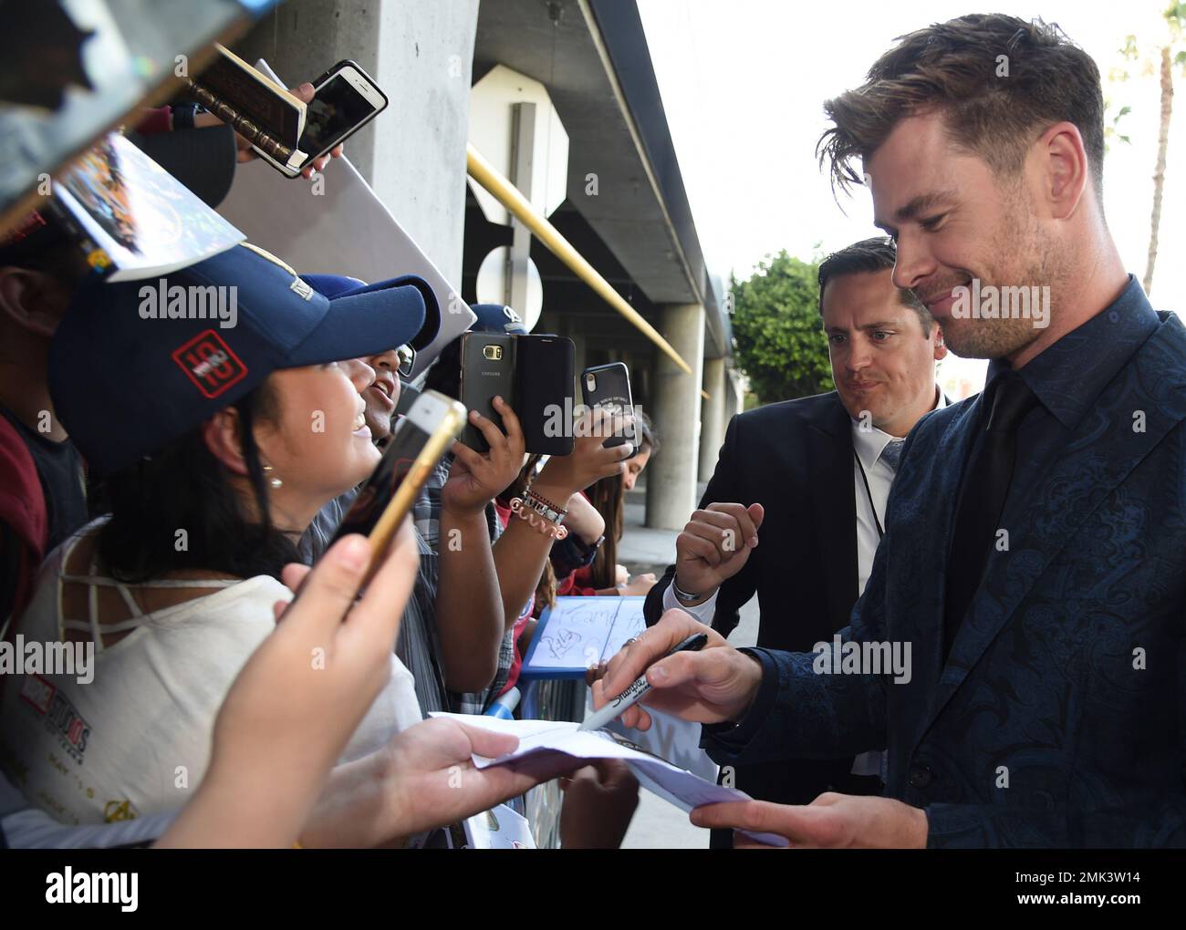 Chris Hemsworth signs an autograph as he arrives at the premiere of ...