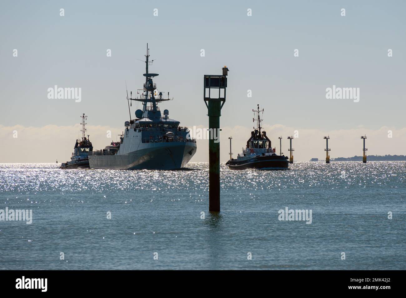 A backlit view of Serco Marine tugs guiding the Royal Navy Ocean Patrol ...