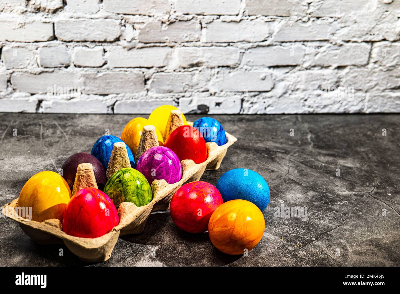 Eggs cardboard with colorful easter eggs in front of white brick wall Stock Photo - Alamy