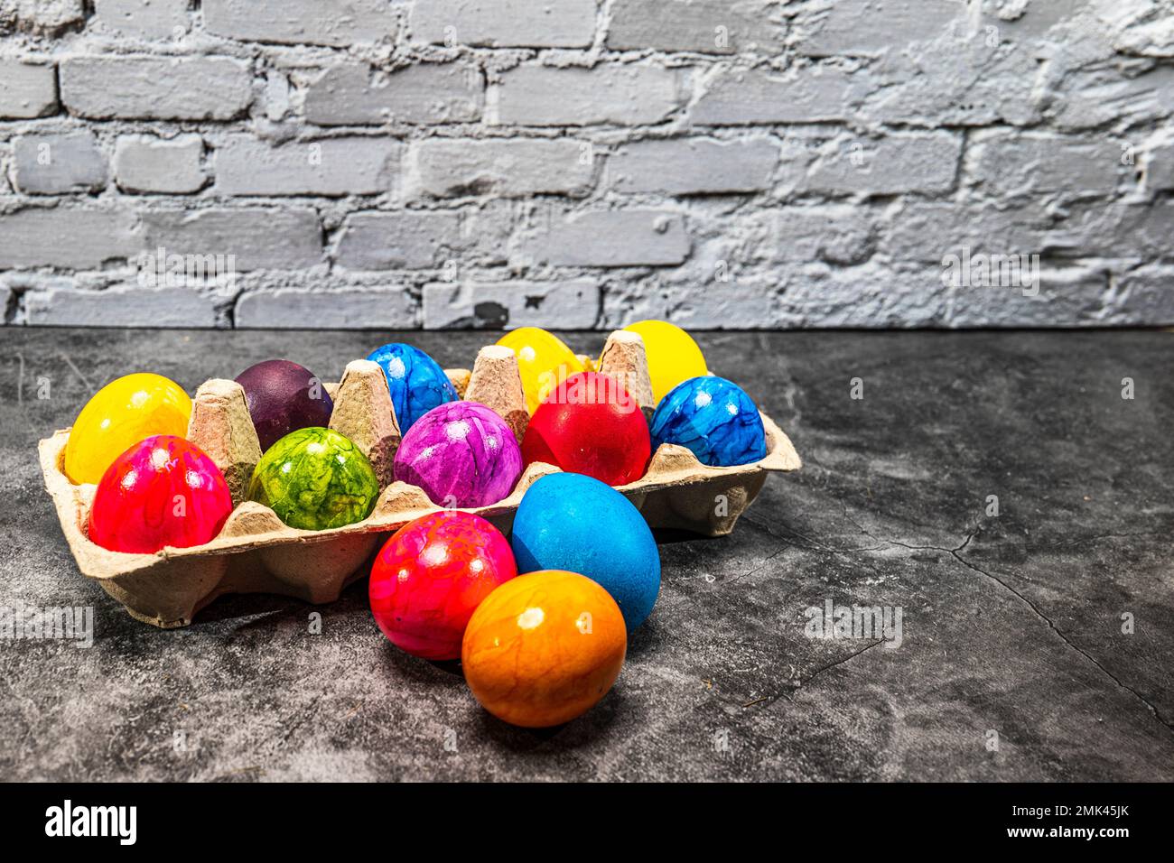 Eggs cardboard with colorful easter eggs in front of white brick wall Stock Photo - Alamy