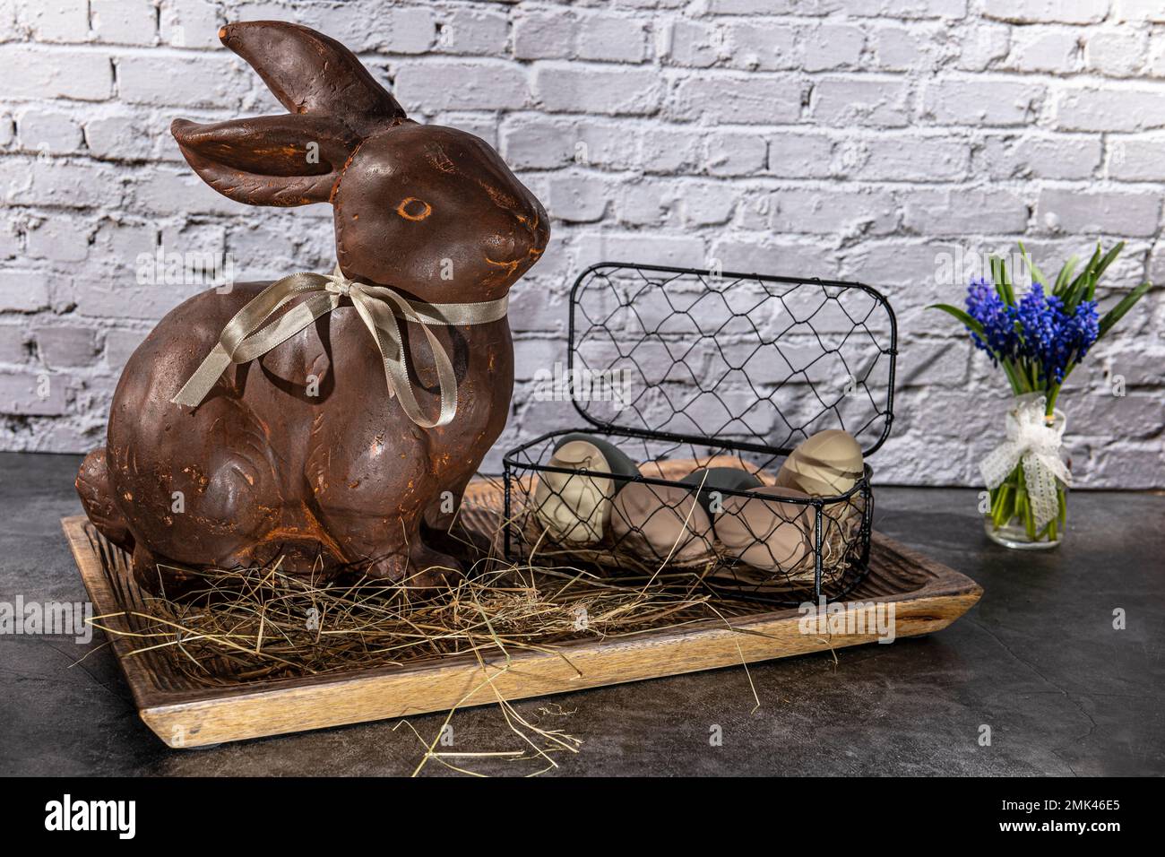 brown clay easter bunny in wooden bowl with easter eggs and hay in ...