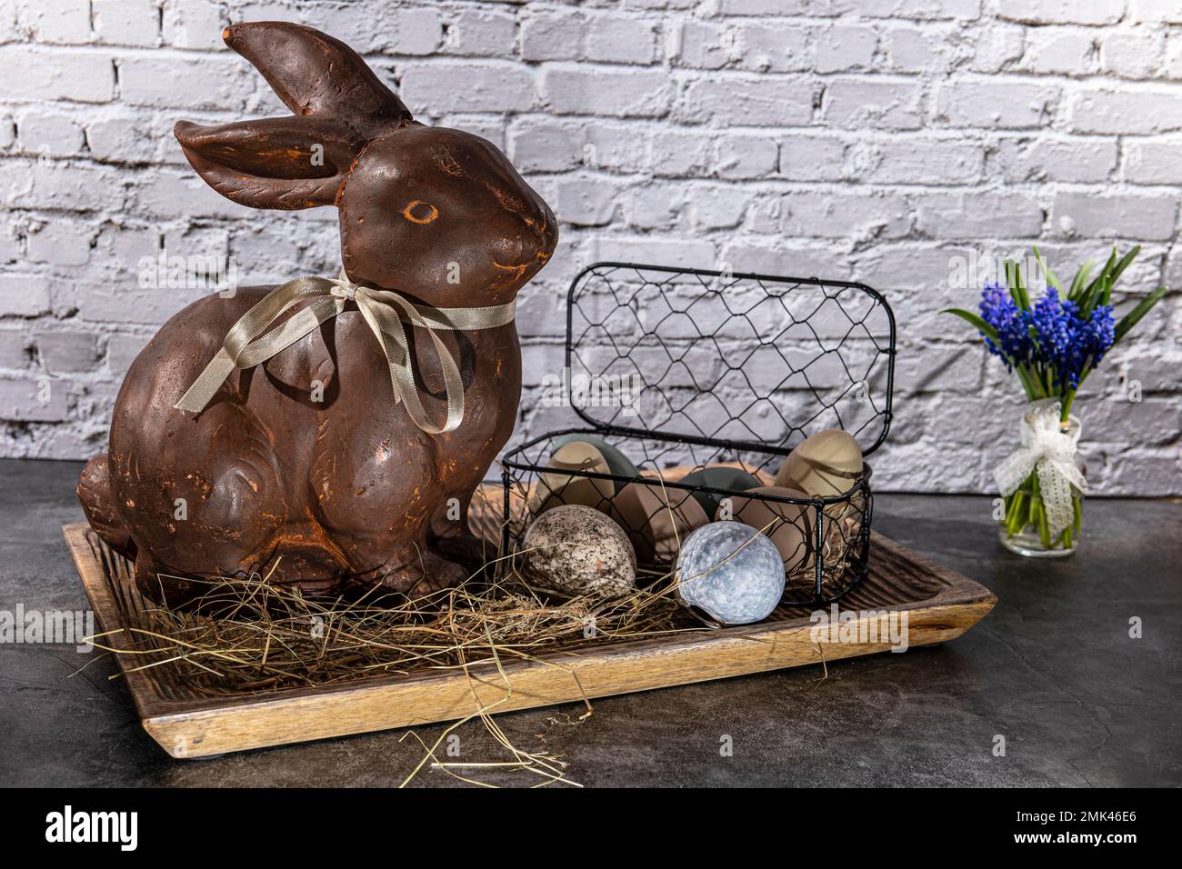 brown clay easter bunny in wooden bowl with easter eggs and hay in ...
